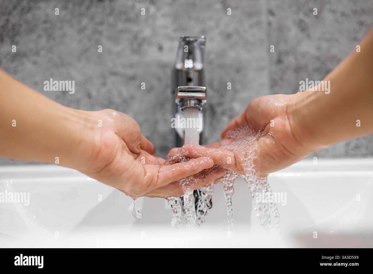 Close-up of hands washing under running water, symbolizing the ...