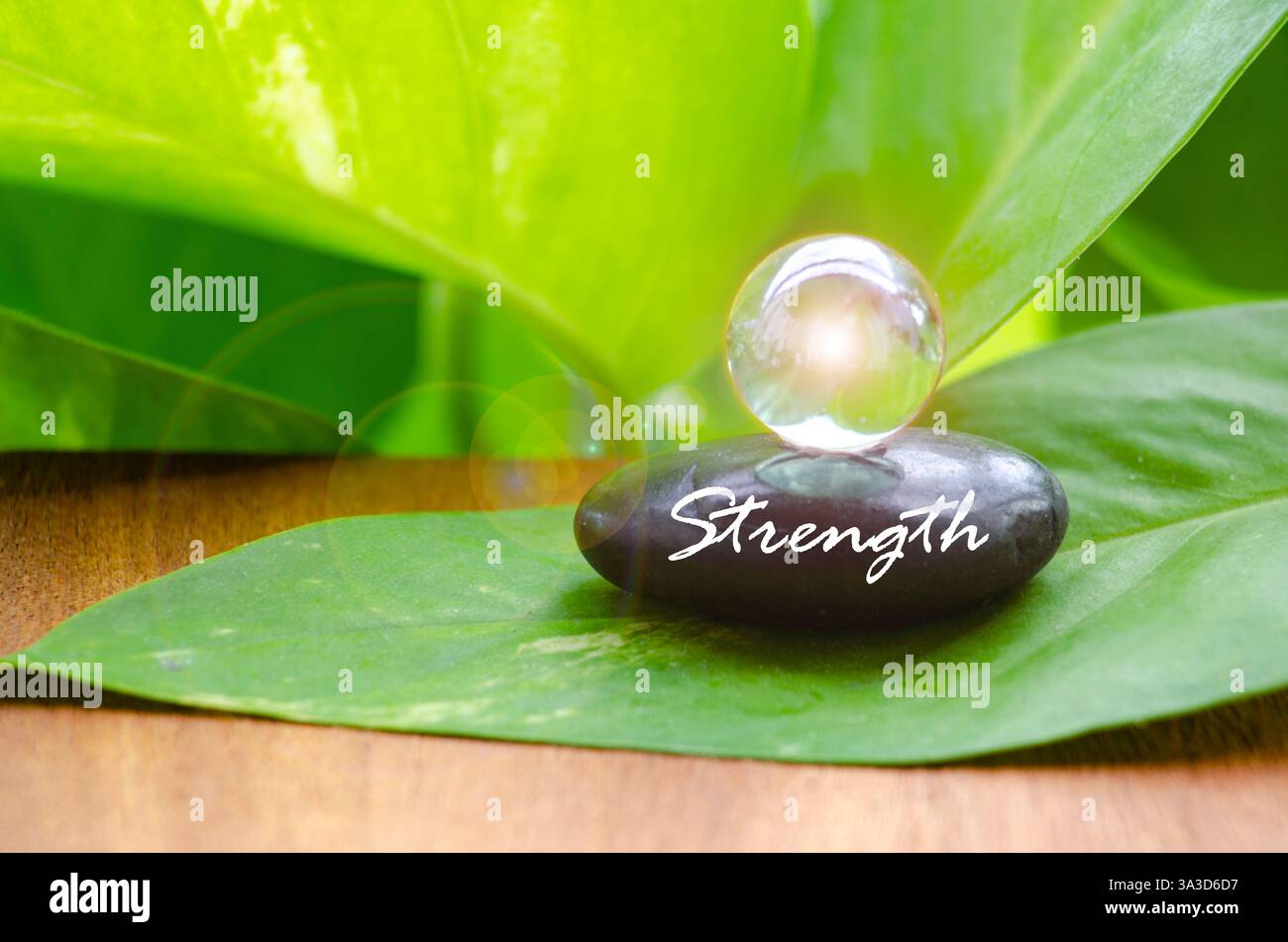 Strength text on zen stone with bright shining glass marble. Inner ...