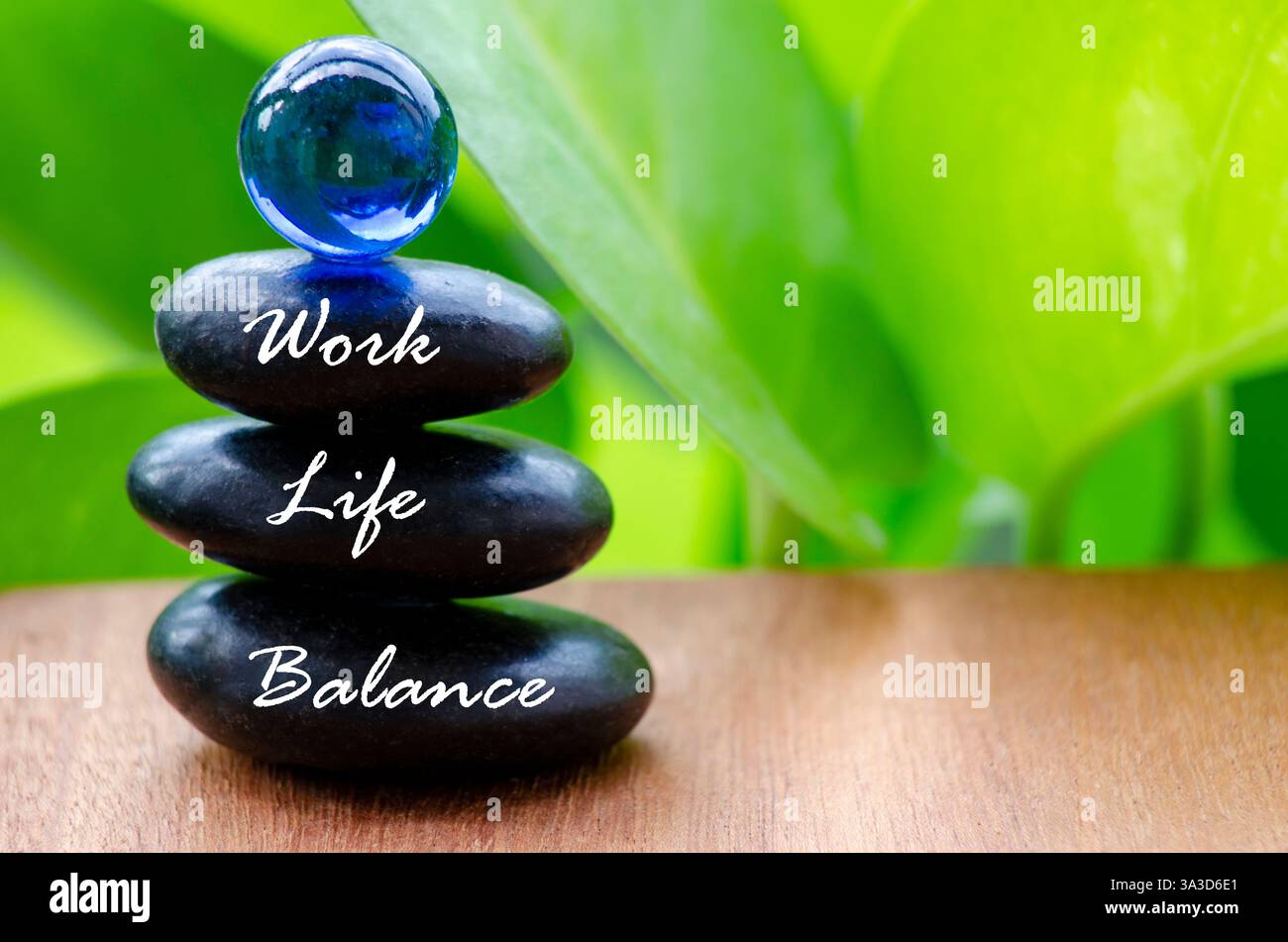 Work Life Balance text on black zen stones with blue glass marble on ...