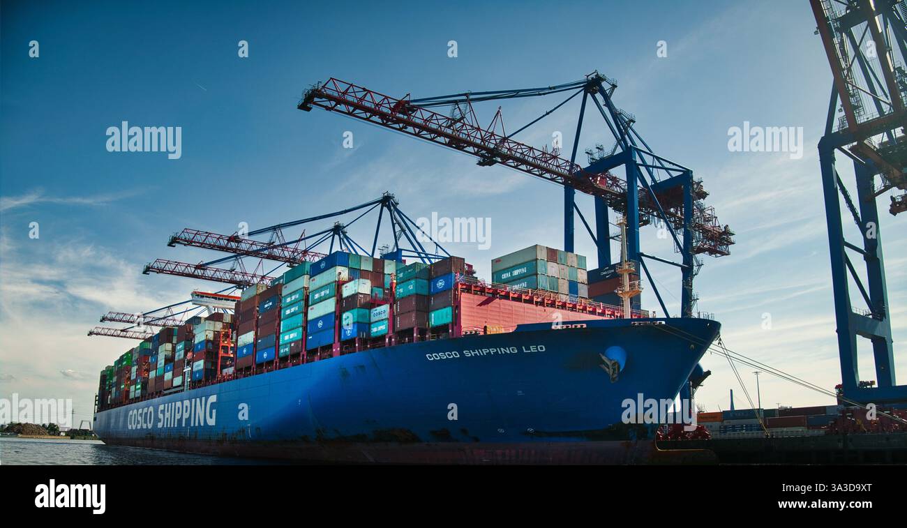 A large container ship is anchored in the Port of Hamburg while massive ...