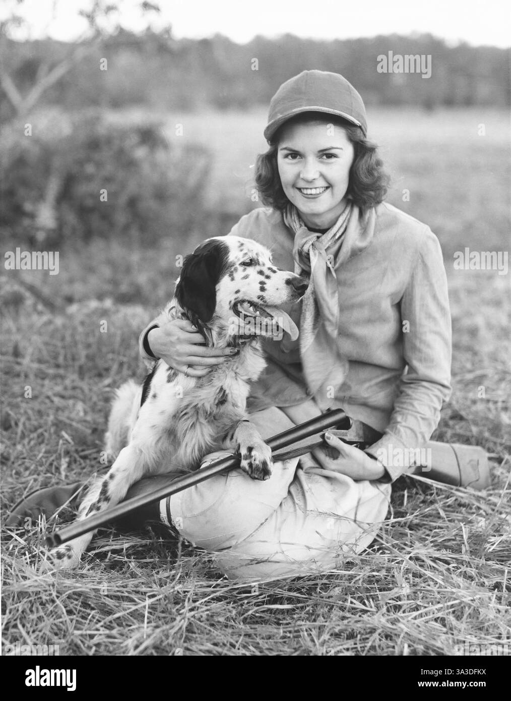 Woman Hunter sitting in the field with her hunting dog and shotgun ...