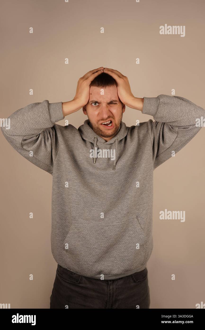 A man holds both hands on his head, a gesture that indicates stress or ...