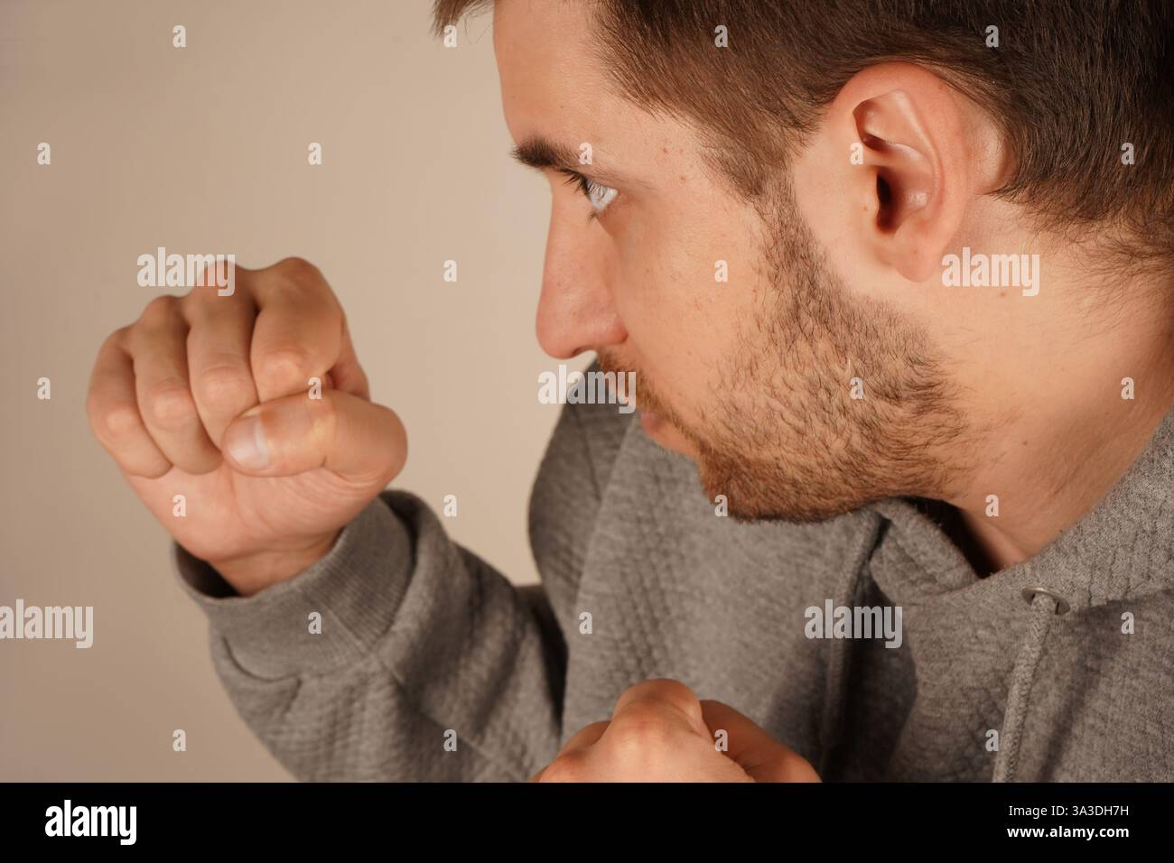 A man in a sporty hoodie stands with clenched fists in a boxing stance ...