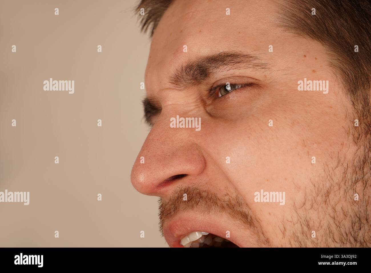 In this close-up, a young man s face displays a disgusted expression ...