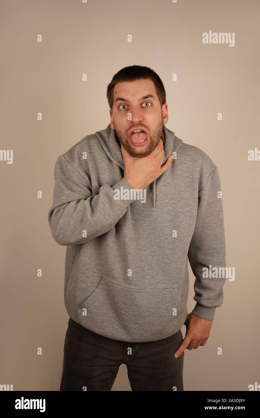 A man grips his throat with his hand, mouth wide open as if he s ...