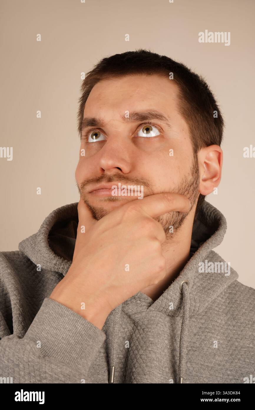 With his hand on his chin, the man appears deep in thought. His gaze ...