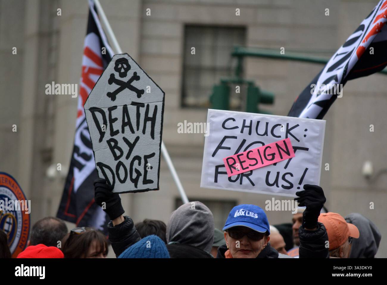 Anti-Chuck Schumer signs at in a Stop the Cuts rally against DOGE cuts ...