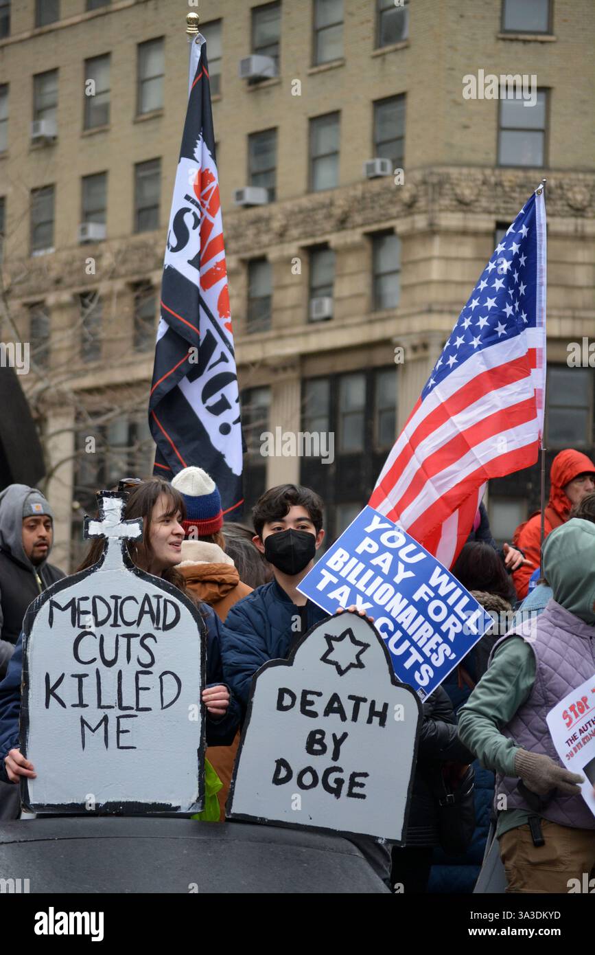 People with signs at a Stop the Cuts rally against DOGE cuts to federal ...