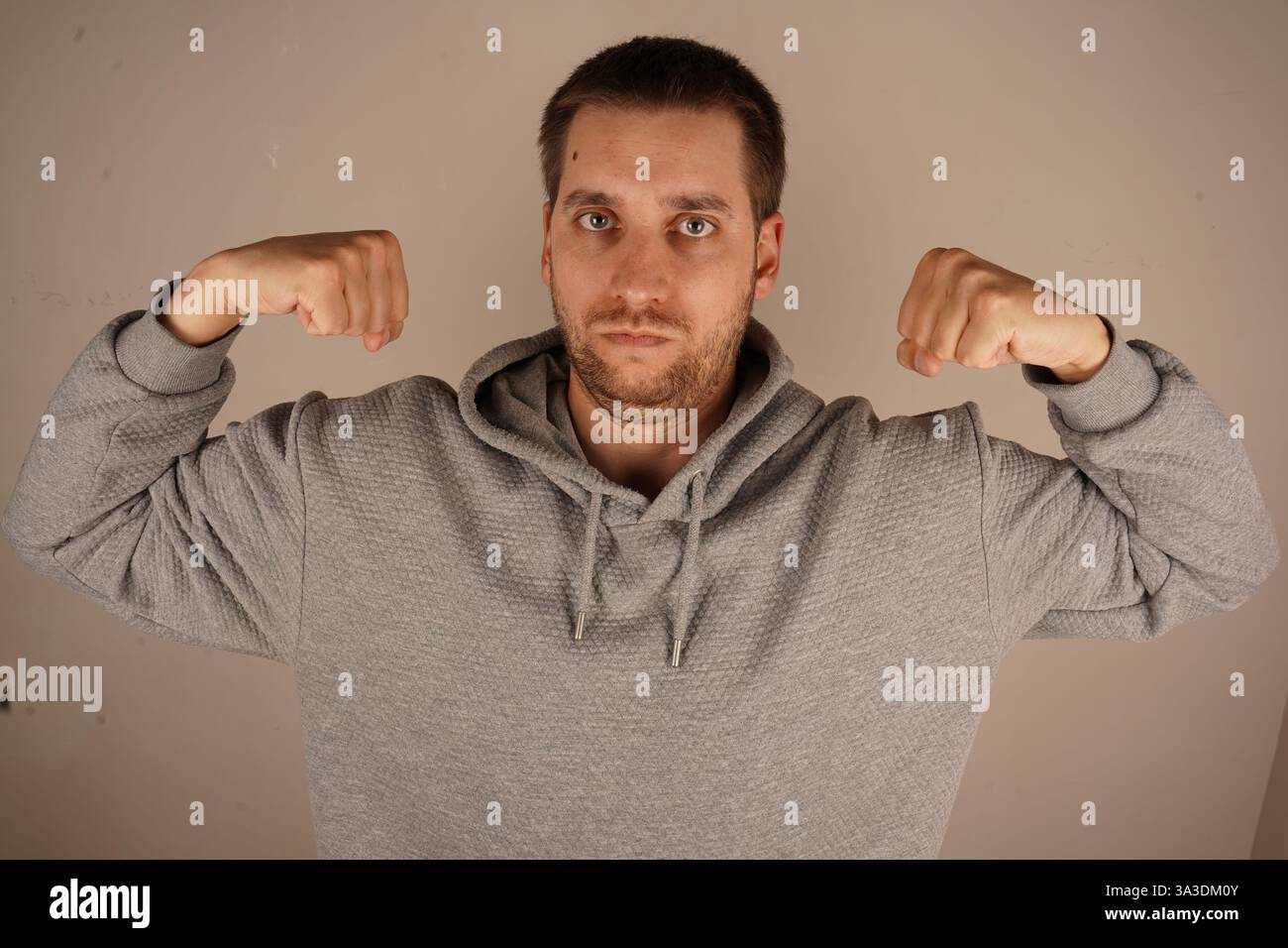 Flexing both arms, the man demonstrates his biceps and clenched fists ...