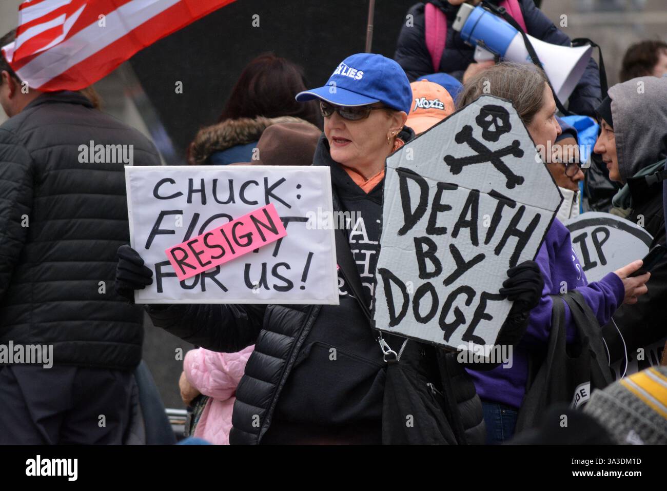 Anti-Chuck Schumer signs at in a Stop the Cuts rally against DOGE cuts ...