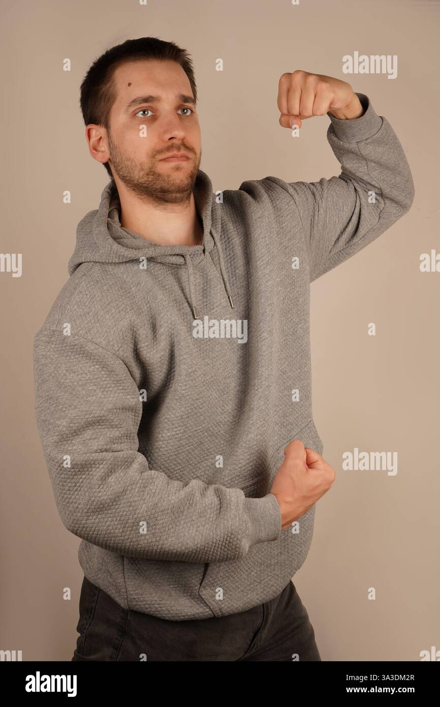 With a cheerful smile, the young man flexes his arm, highlighting his ...