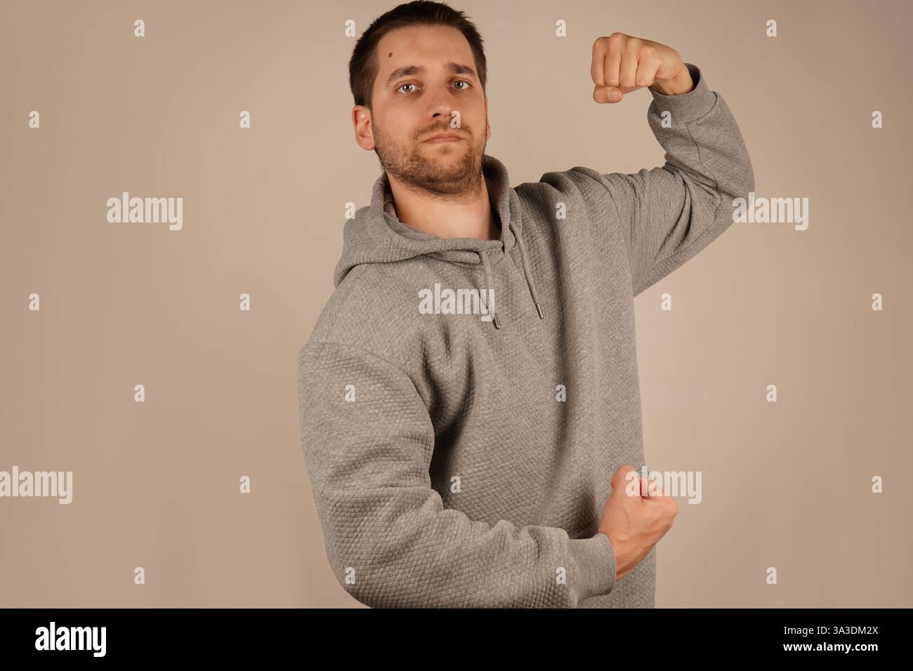 With a cheerful smile, the young man flexes his arm, highlighting his ...