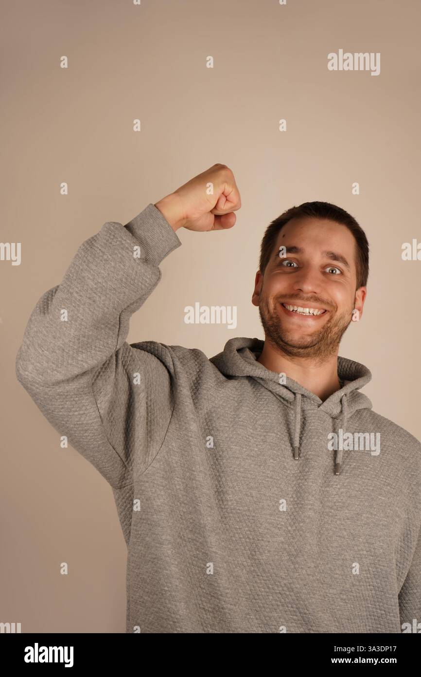 The man, with a wide grin, lifts his fists in celebration, expressing ...