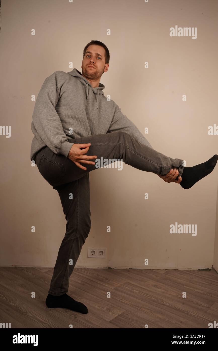 The man, smiling broadly, mimics playing the guitar with his leg. His ...