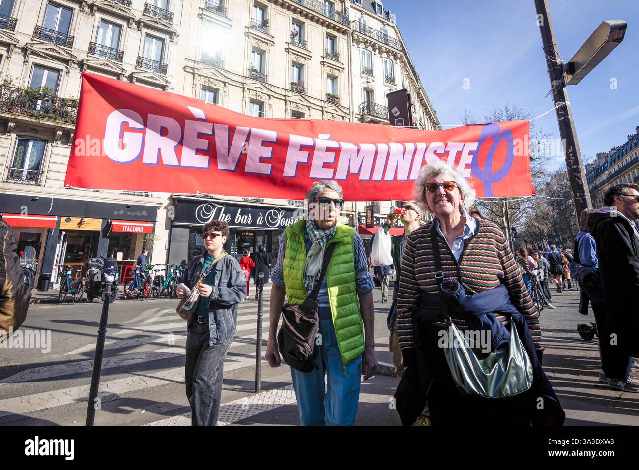 Women pass near a banner that says "Feminist Strike" during the ...
