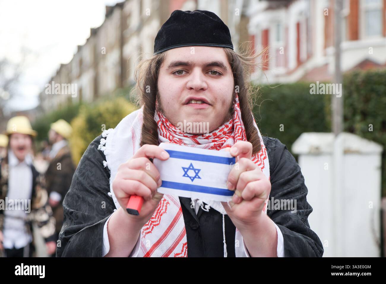 London, UK. 14th Mar, 2025. An Orthodox Jewish boy holds a mini flag of ...