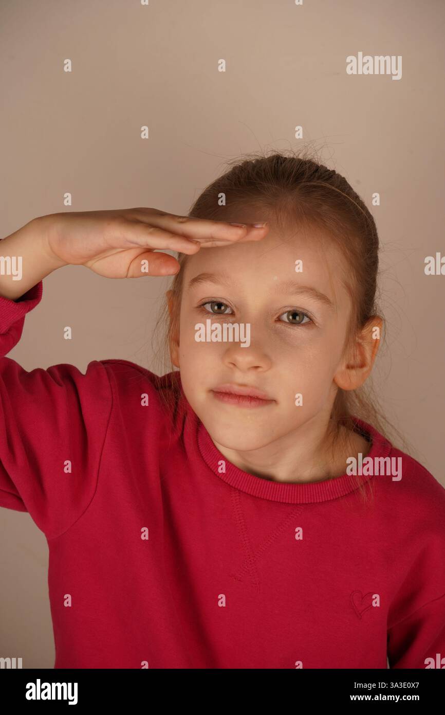 The girl raises her hand to her forehead, shielding her eyes from the ...