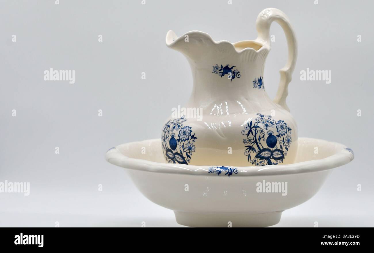 A decorative ceramic pitcher is placed beside a matching basin, both ...