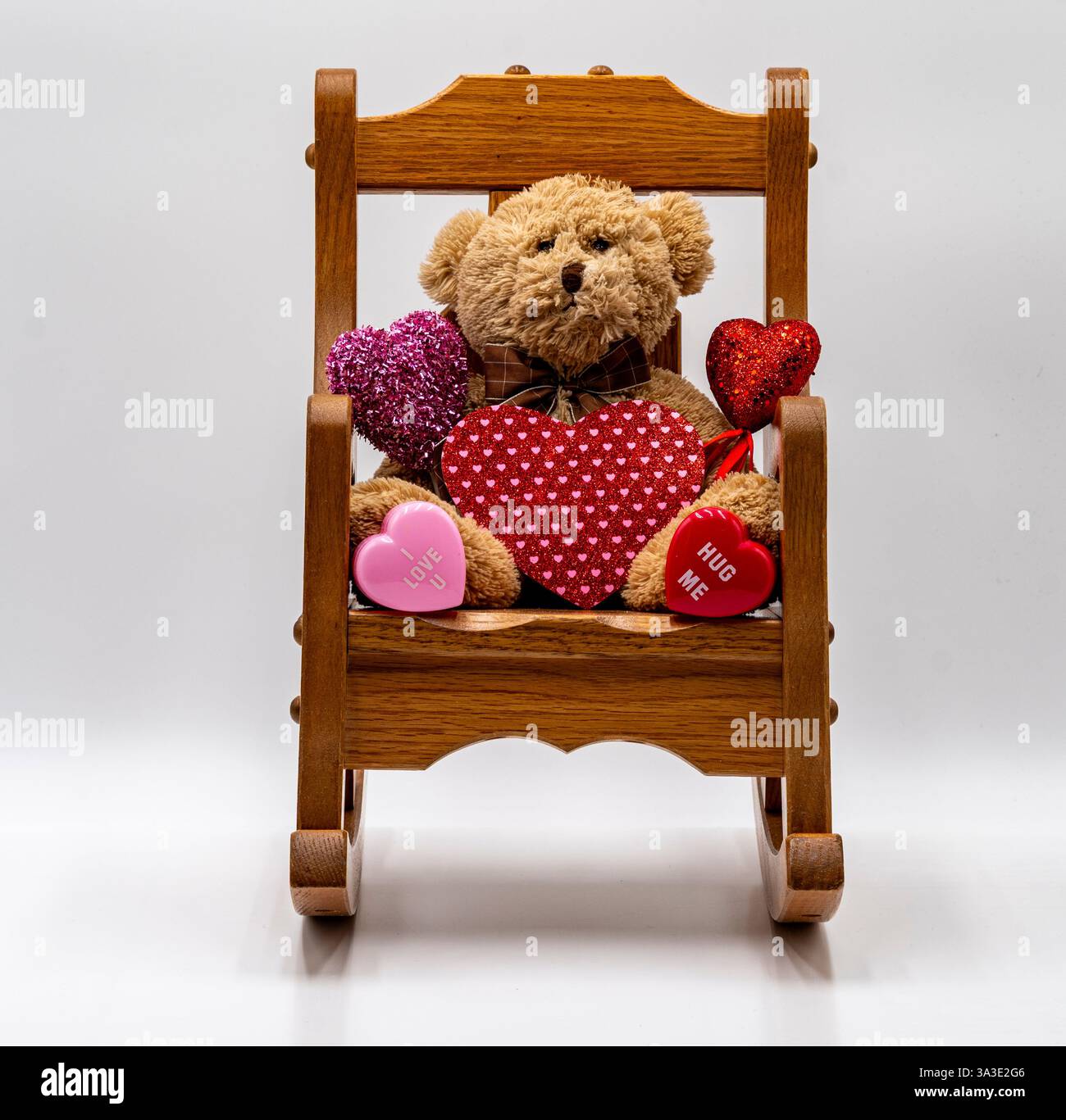 A plush teddy bear sits in a wooden rocking chair, surrounded by ...