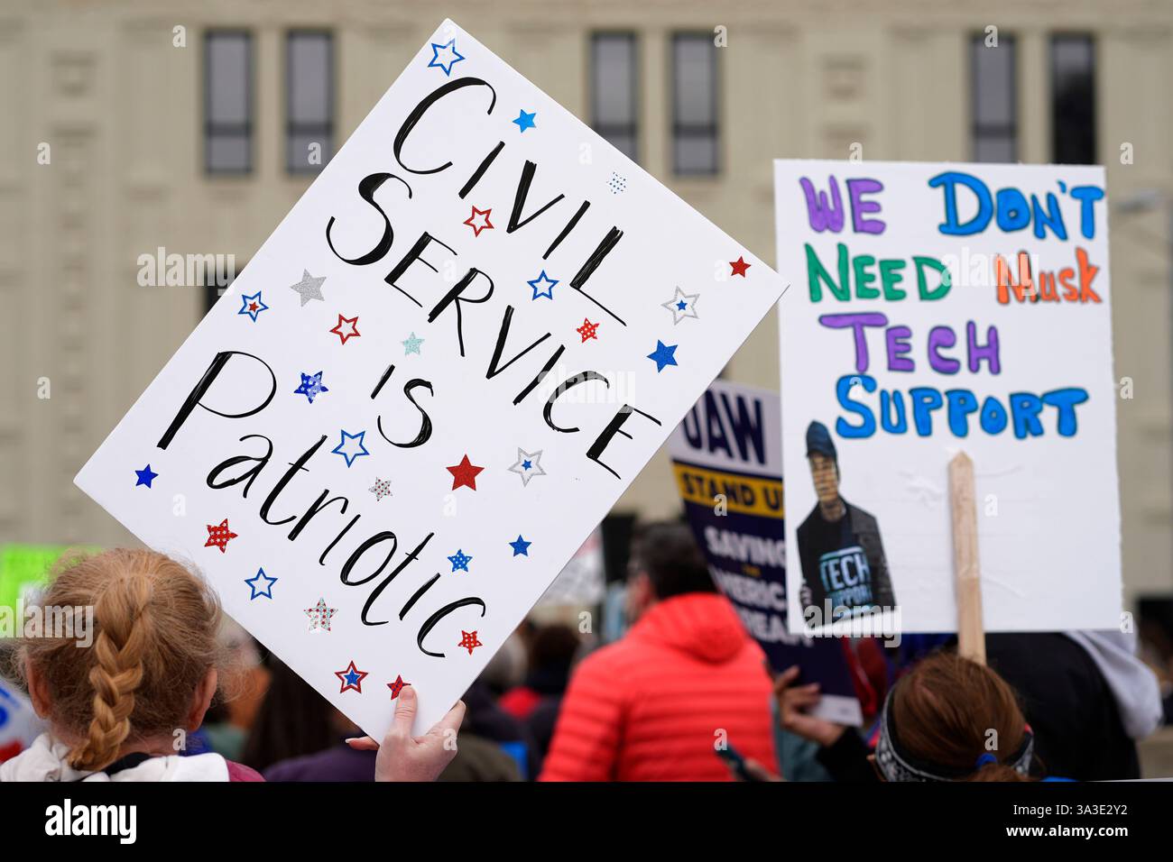 People hold signs at a rally supporting federal workers outside the IRS ...
