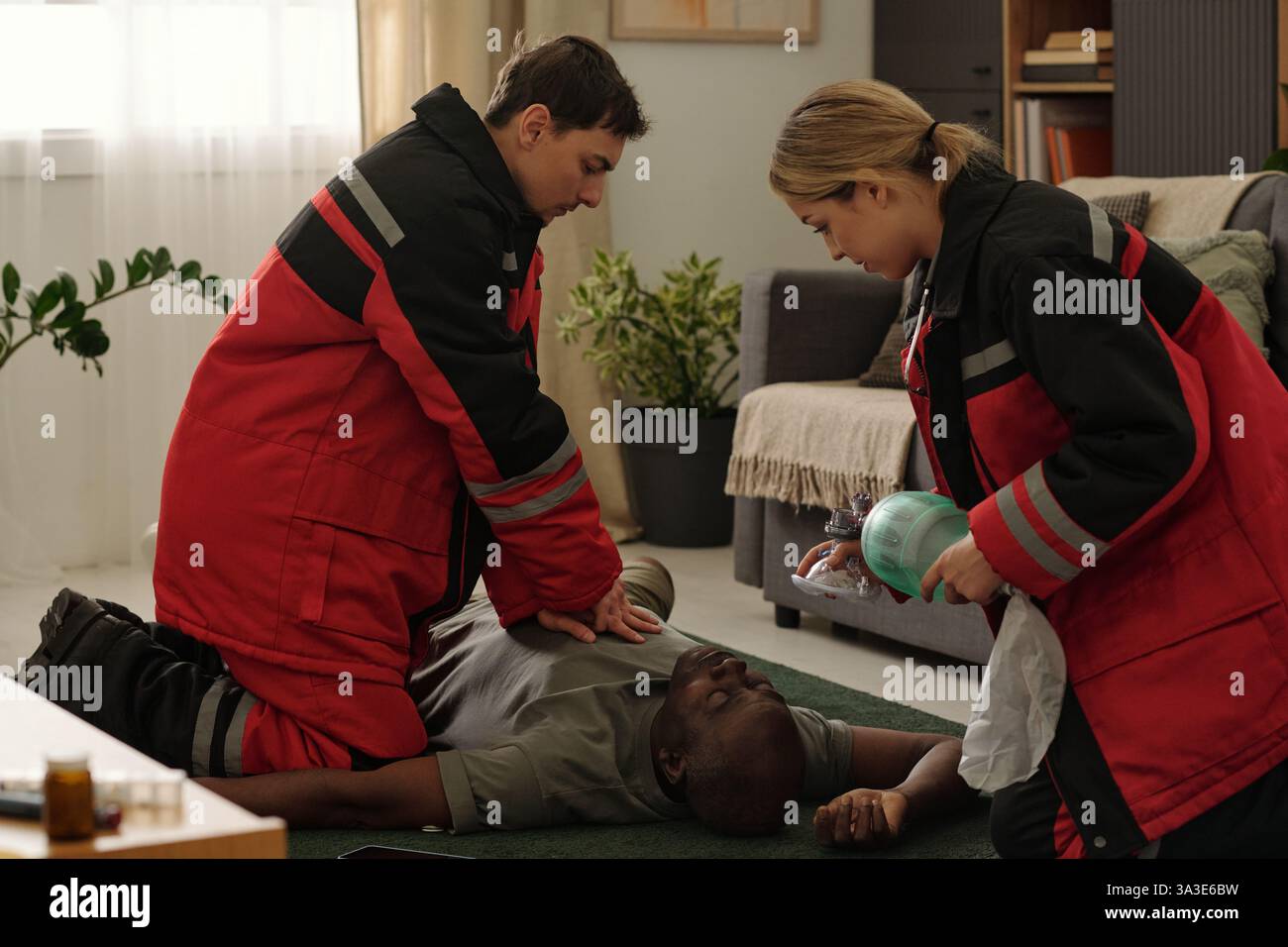 Emergency responders assisting unconscious man lying on floor in modern ...