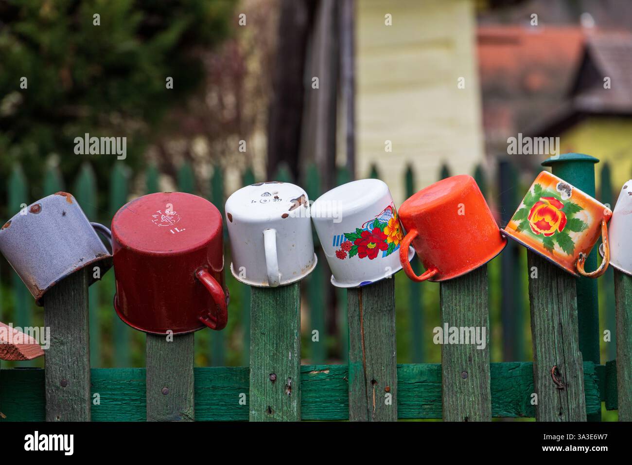 Metal mugs on a wooden fence in the traditional village of Vlkolínec ...