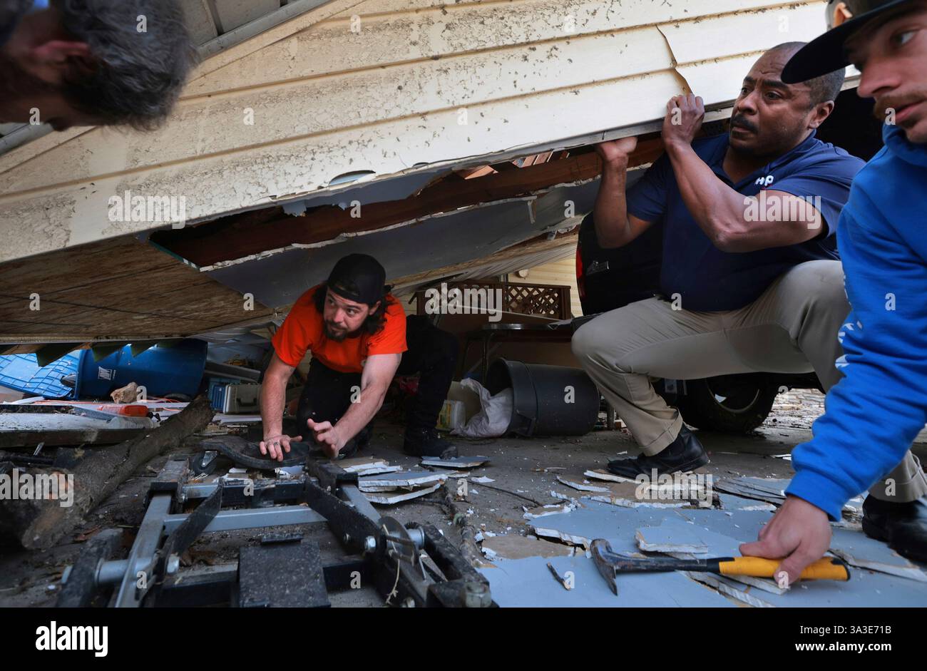 Matt Wolff, left, works underneath his carport with the help of his ...