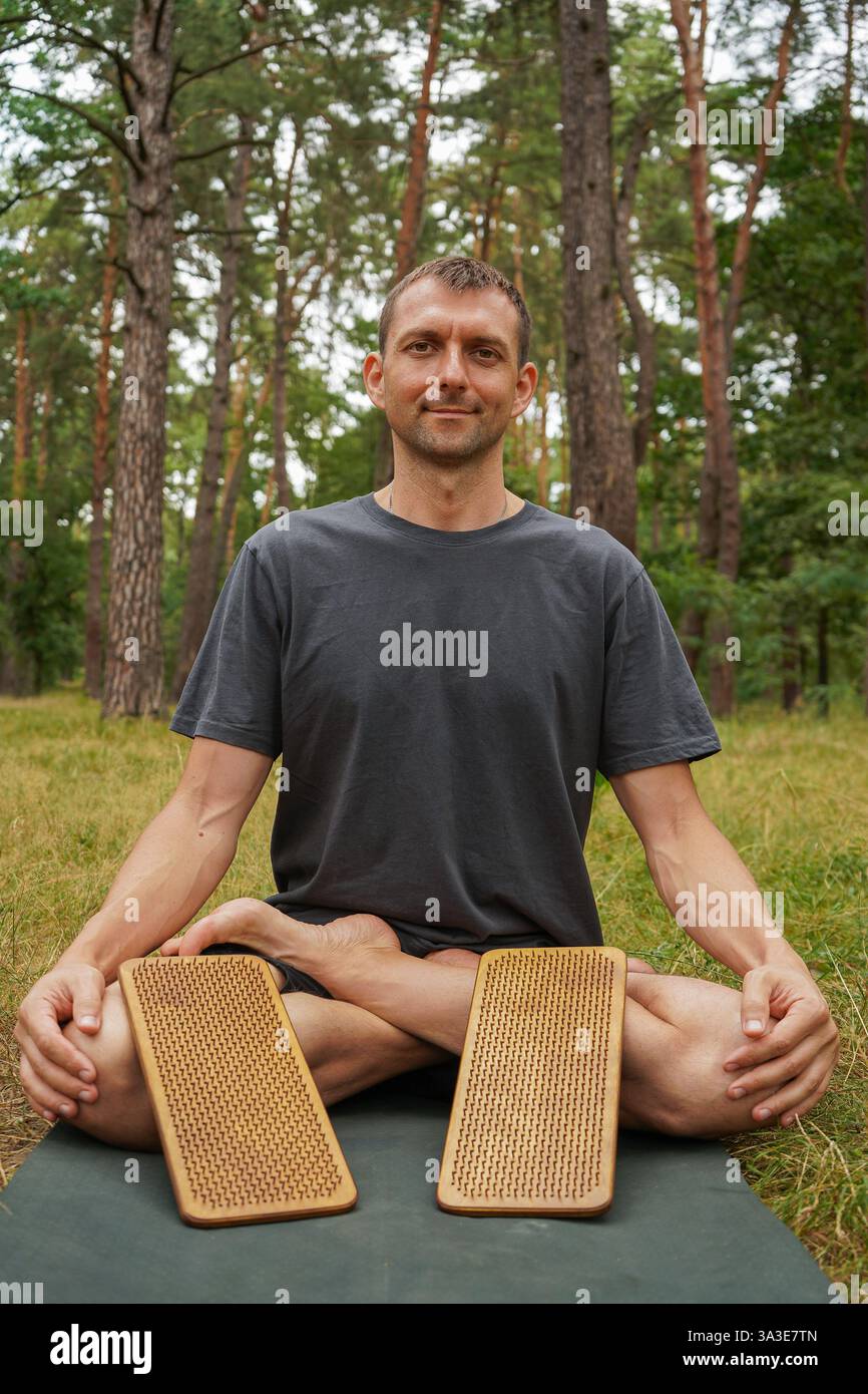 A man practicing meditation in a serene forest, sitting cross-legged on ...
