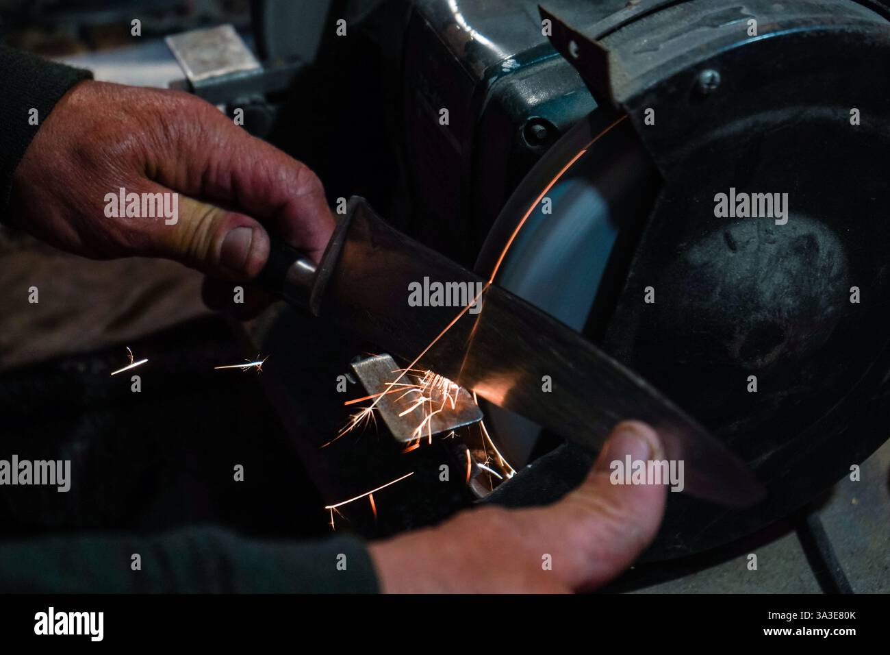 Sparks illuminate the dark workshop. The image conveys precision and ...