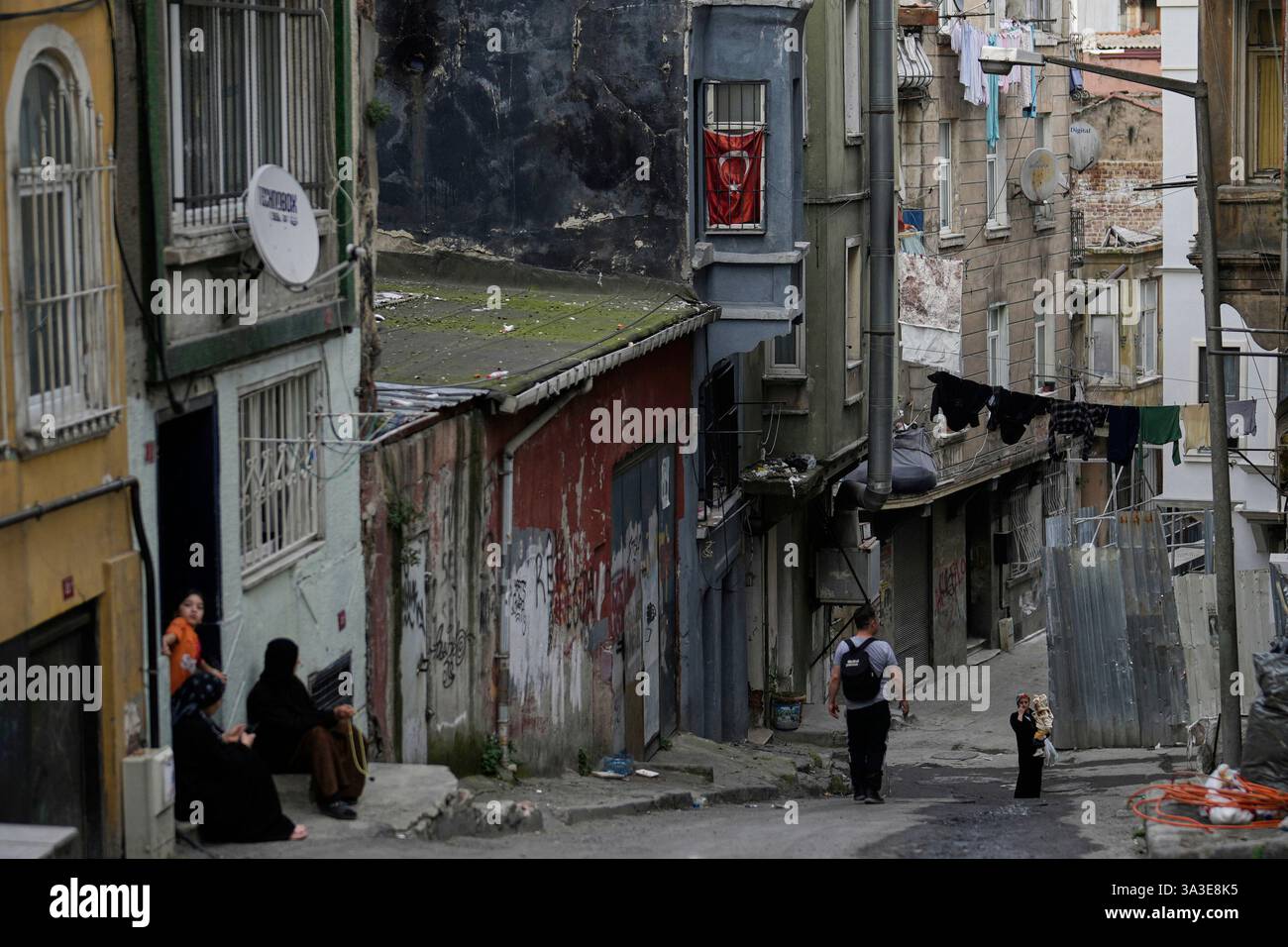 People walk through a street in a poor neighborhood in Istanbul, Turkey ...