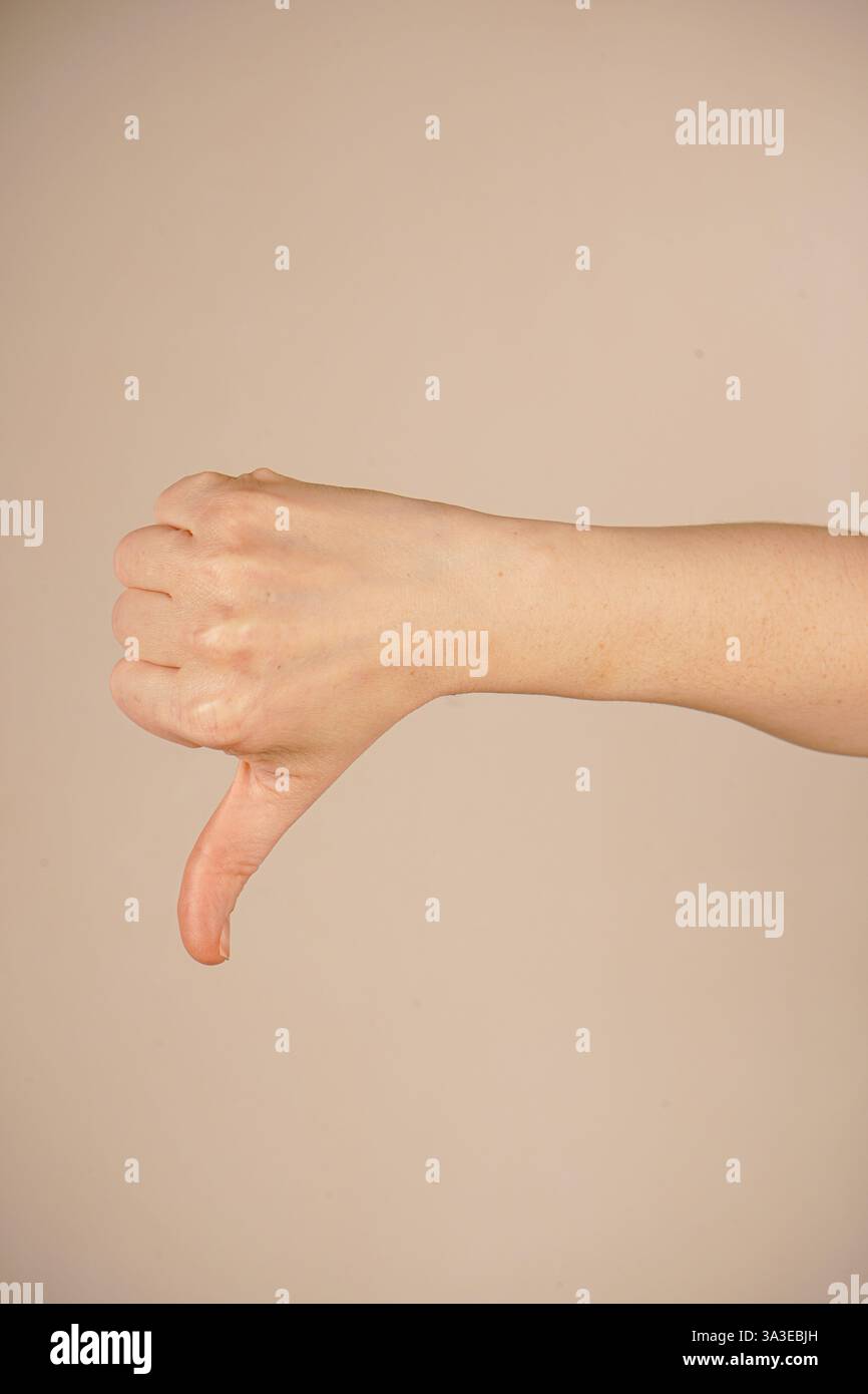 Thumbs down gesture shows dislike. Neutral background focuses the ...