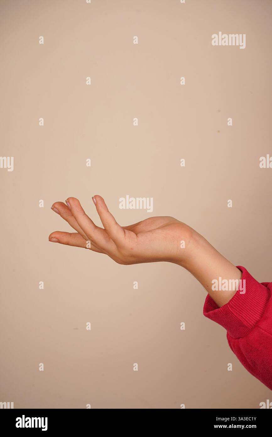The hand is extended with the palm facing up. On a light background of the wall, the hand is up ...