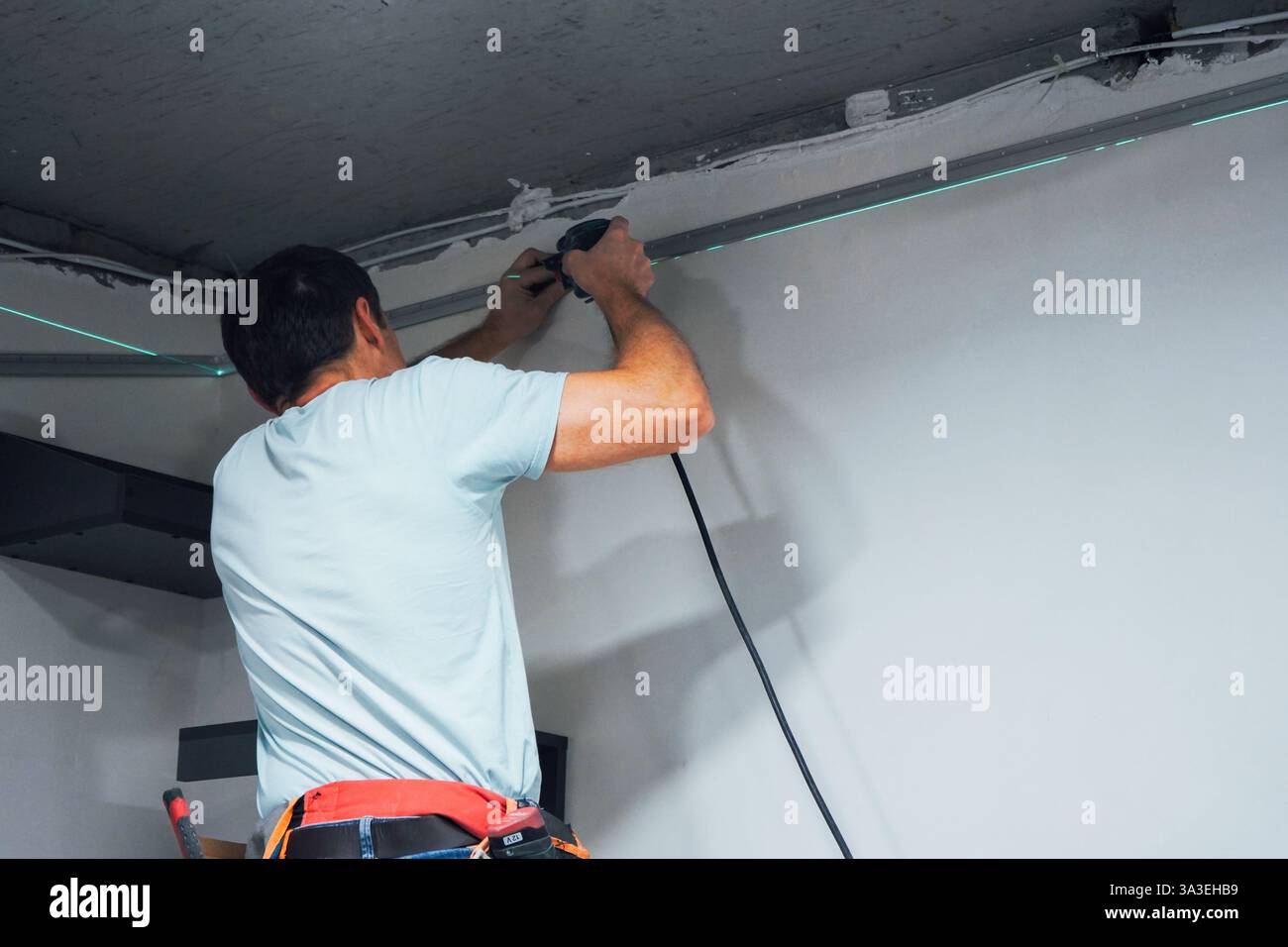 Standing on a ladder on the floor, the craftsman works carefully ...