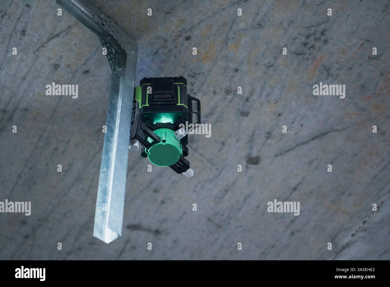 The laser level projects a bright green line onto a smooth white ...