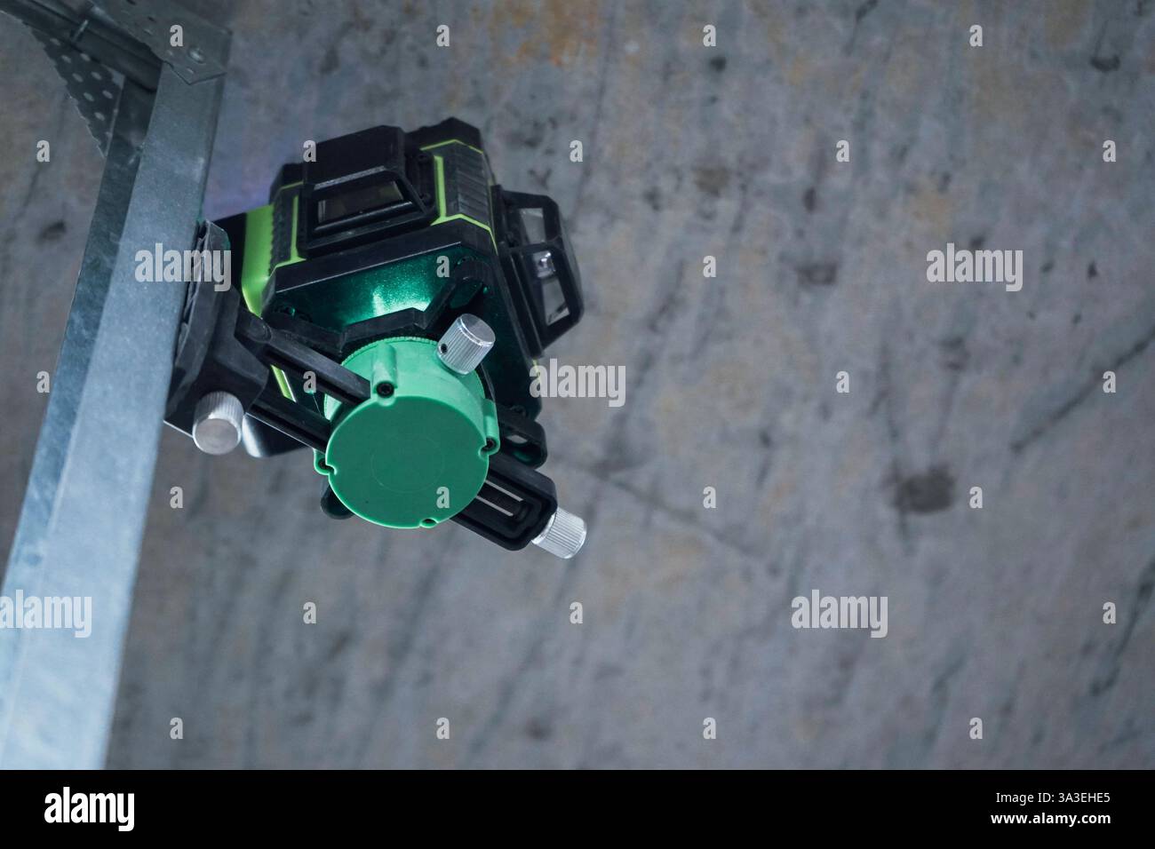 A tripod-mounted laser level draws intersecting lines on the ceiling to ...