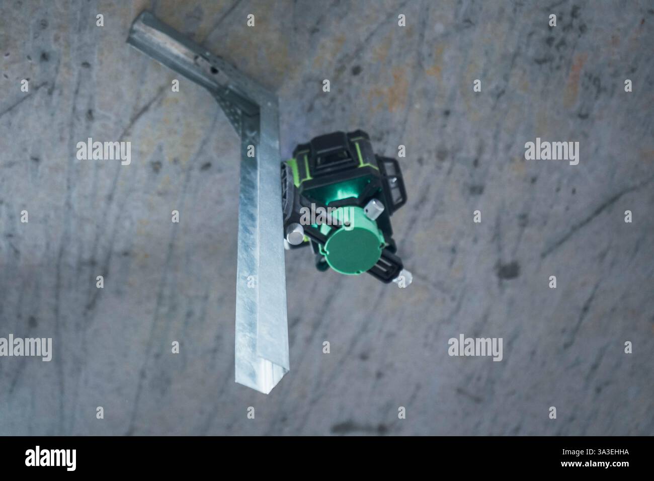 A green beam from a ceiling laser level helps to precisely align a ...
