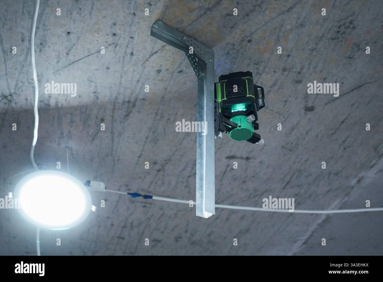 A laser level is mounted on the unfinished ceiling, ready for precise ...