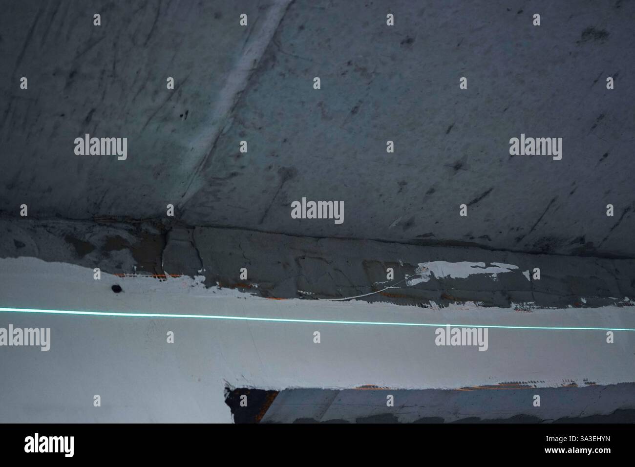 In a space with concrete walls, the green laser level highlights ...