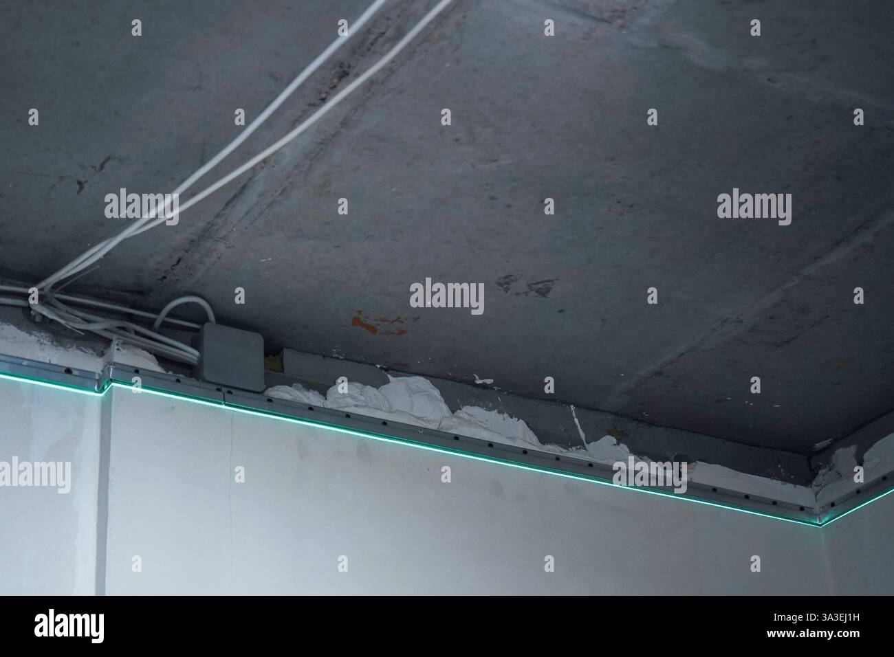 A handheld laser level projects a single green line onto the ceiling ...