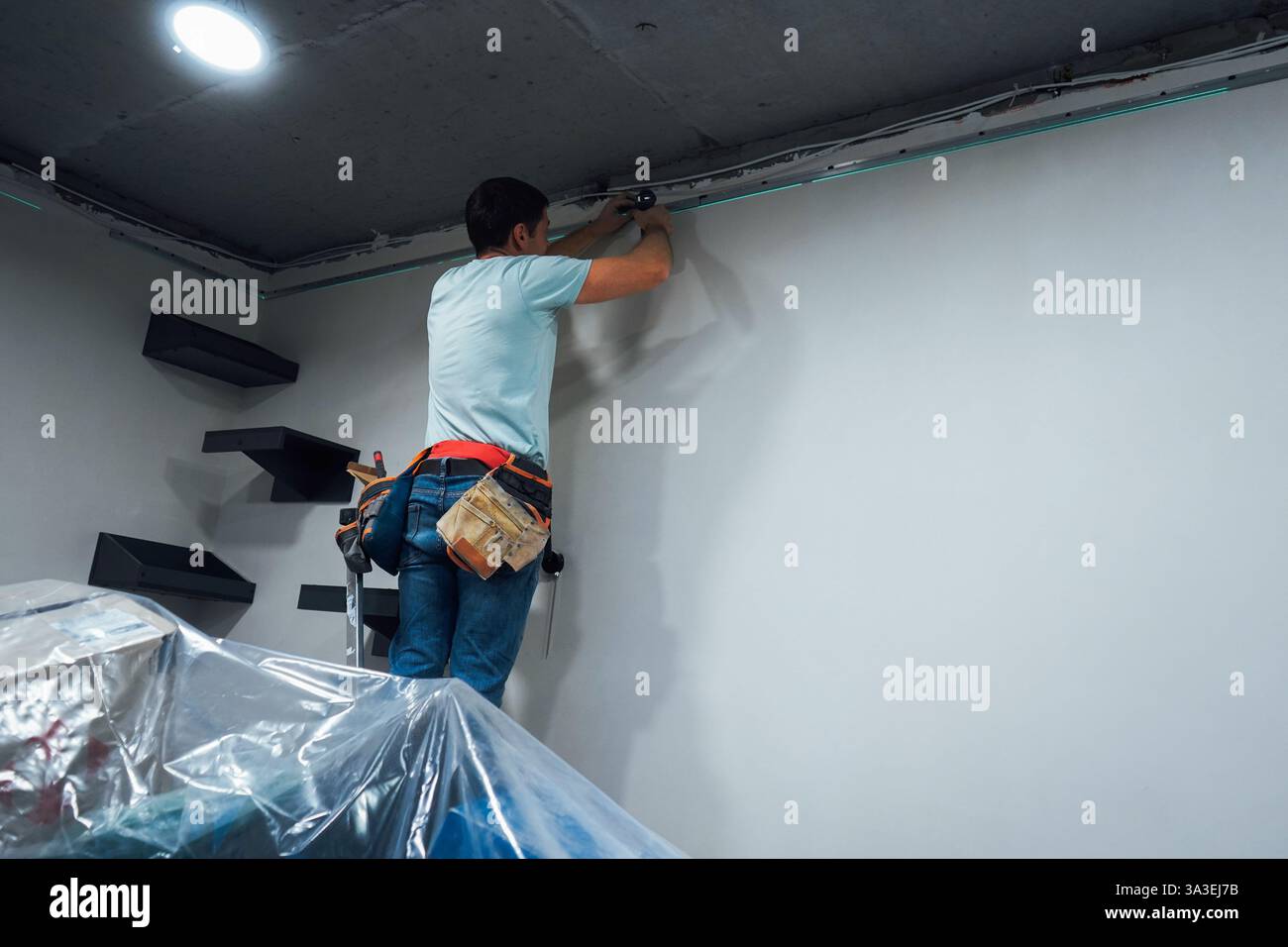A man drills into a drywall ceiling. He shows off his professionalism ...