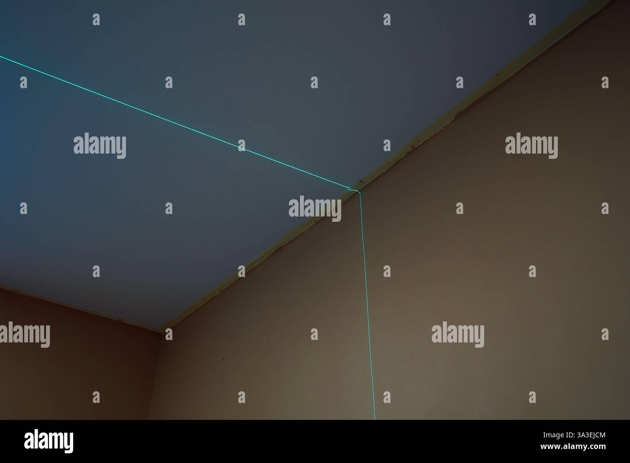 On a dusty floor, the green laser level casts intersecting beams onto ...