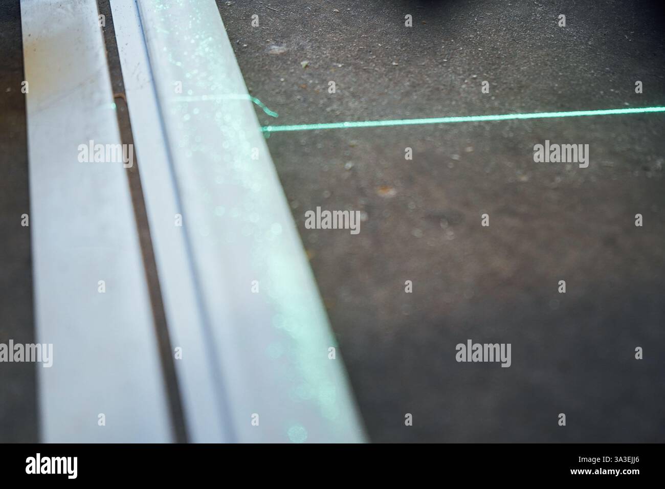 In the center of the room, two green laser lines merge on the concrete ...