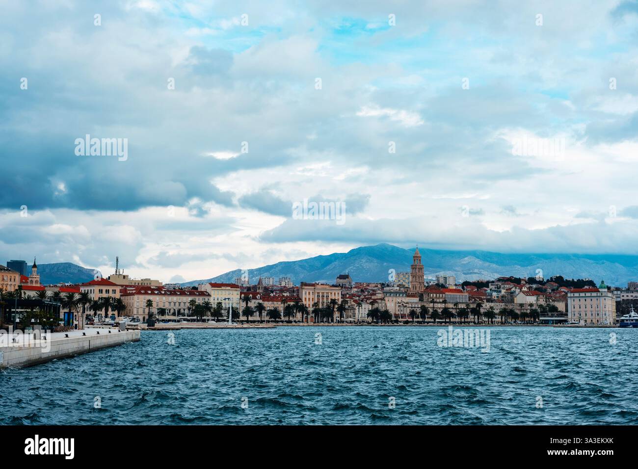 Coastal cityscape with mountains and cloudy sky over blue sea. Split ...