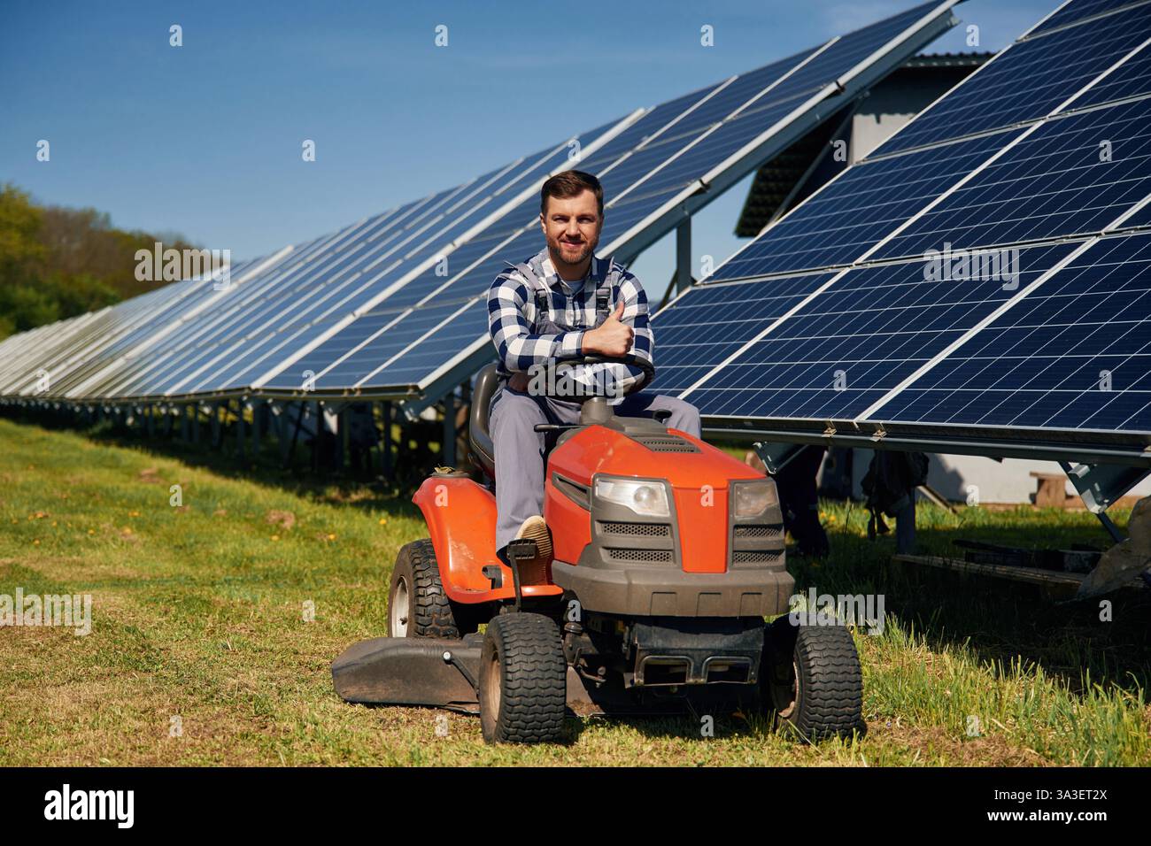 Rides a lawnmower. Engineer with photovoltaic solar panels outdoors at ...
