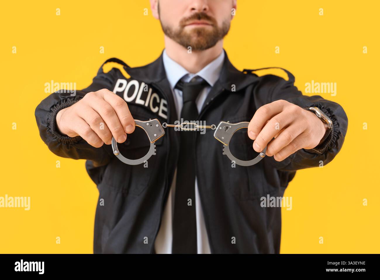 Male police officer with handcuffs on yellow background, closeup Stock ...