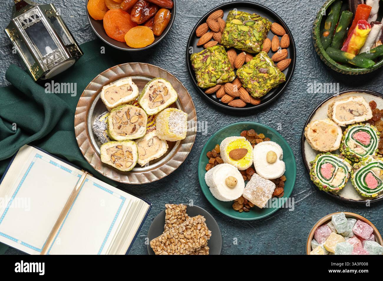 Composition with different Eastern sweets, Koran and lantern on dark ...