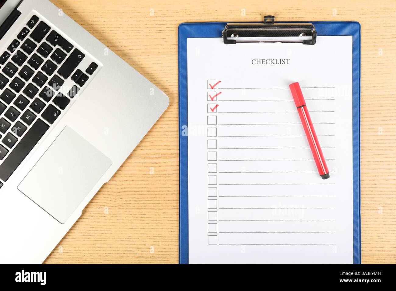 Checklist with checkboxes, marker and laptop on wooden table, flat lay ...