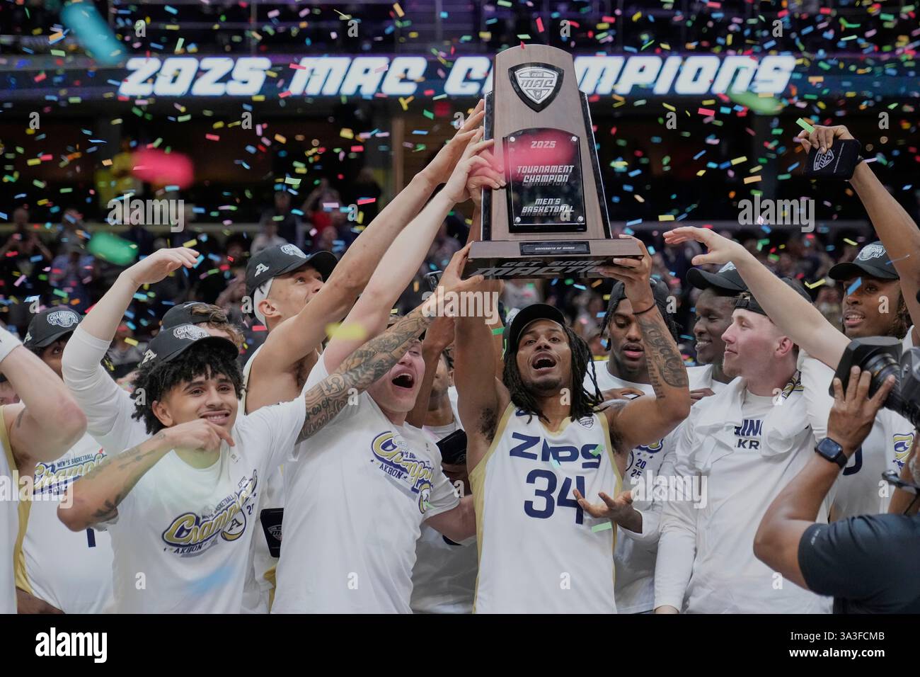 Akron guard Nate Johnson (34) holds the trophy and celebrates with ...