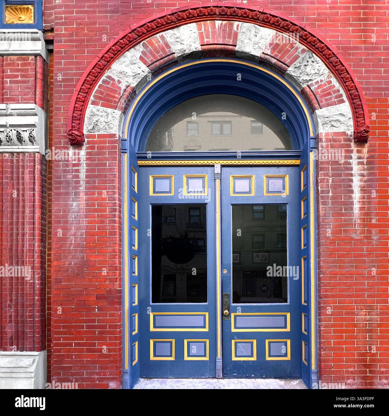 Elegant blue and gold double doors set within a red brick arched ...