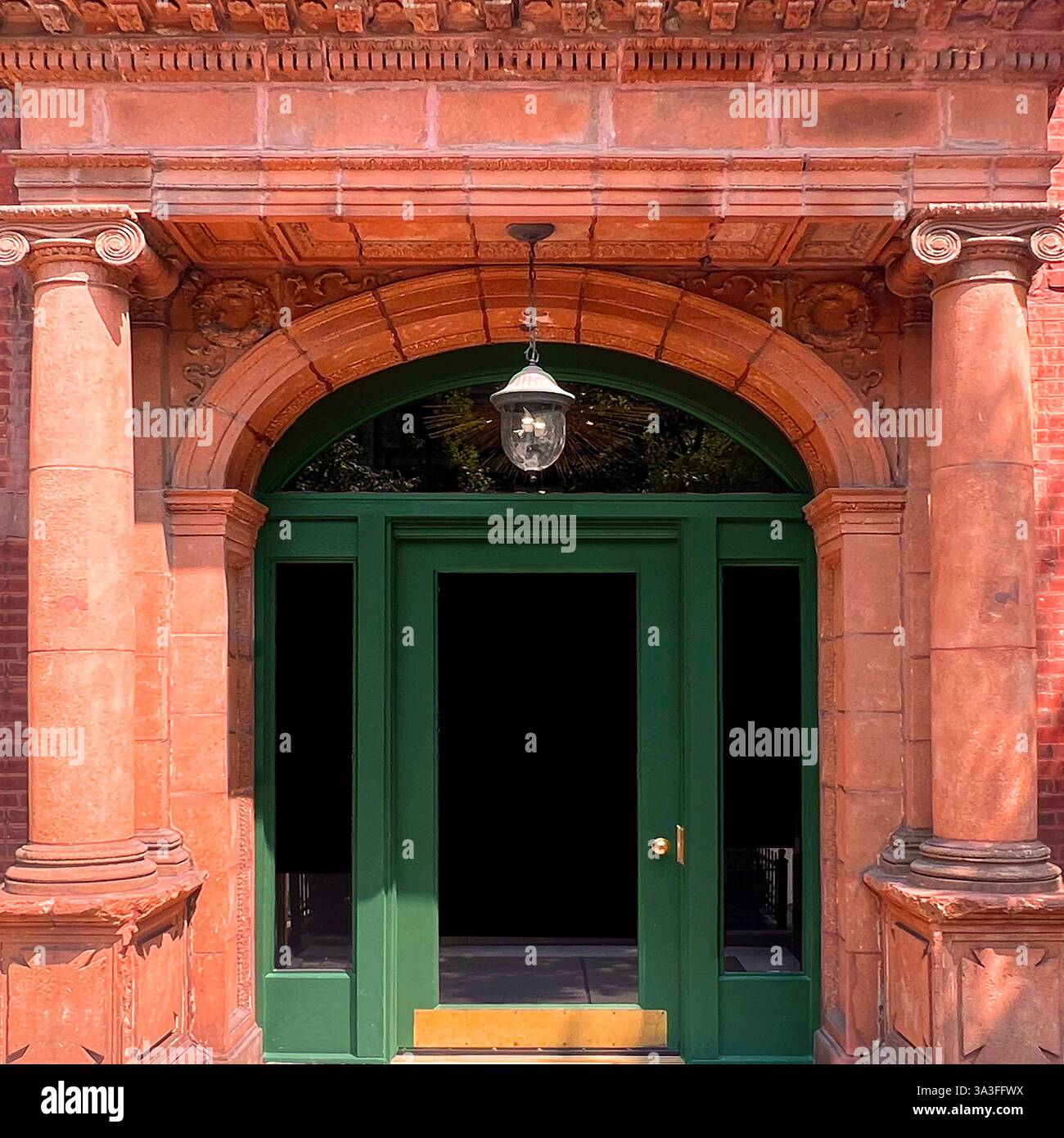 Arched entrance with a deep green door framed by ornate red sandstone ...